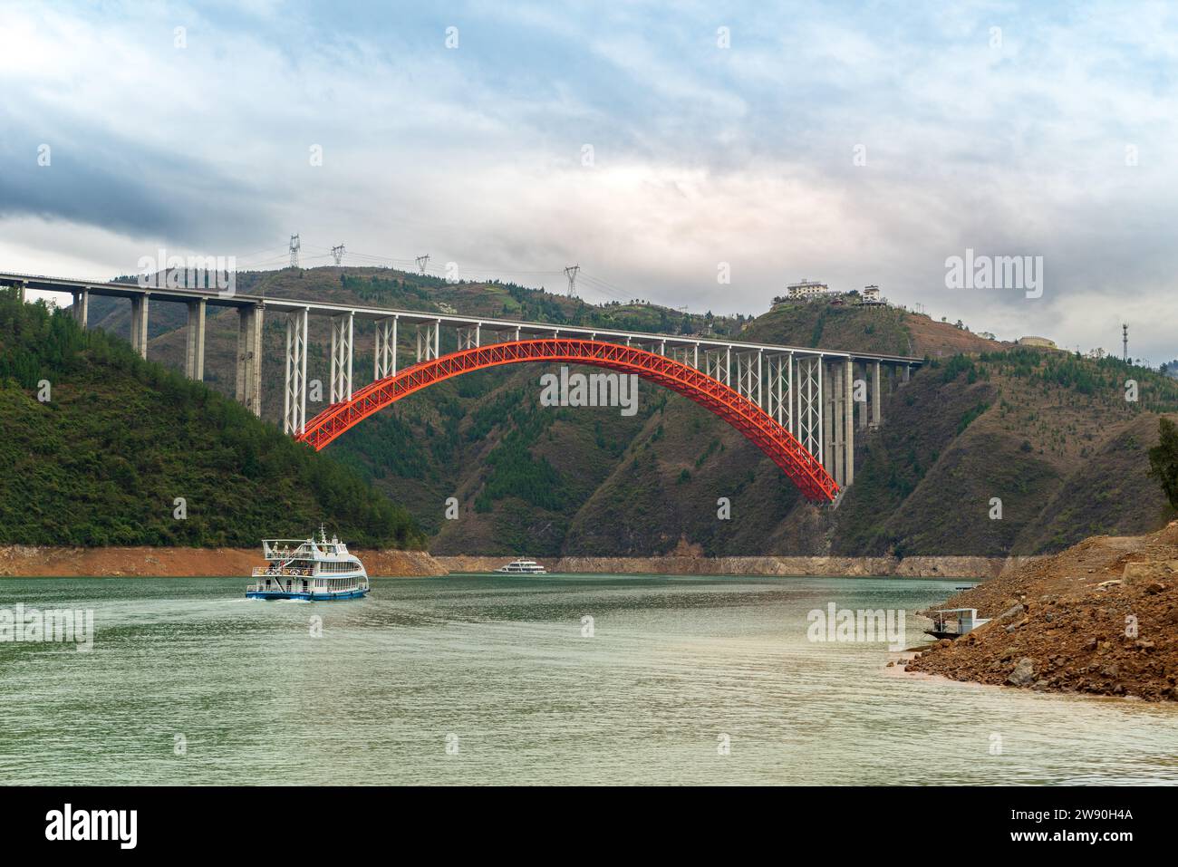 A stunning view of a vibrant red bridge arching over the calm waters of ...