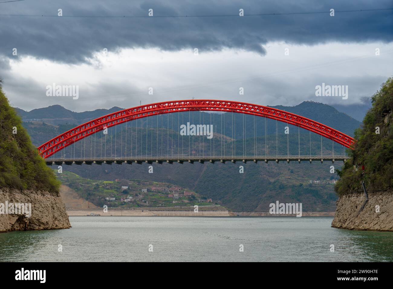 A stunning view of a vibrant red bridge arching over the calm waters of ...