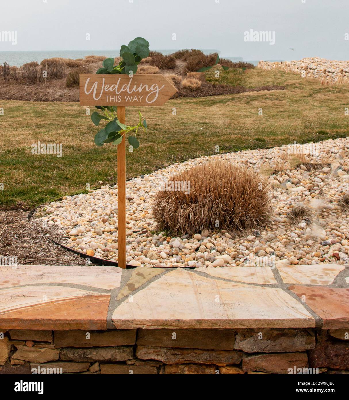Wooden Sign Resting on Stone Wall pointing in the direction of the ...
