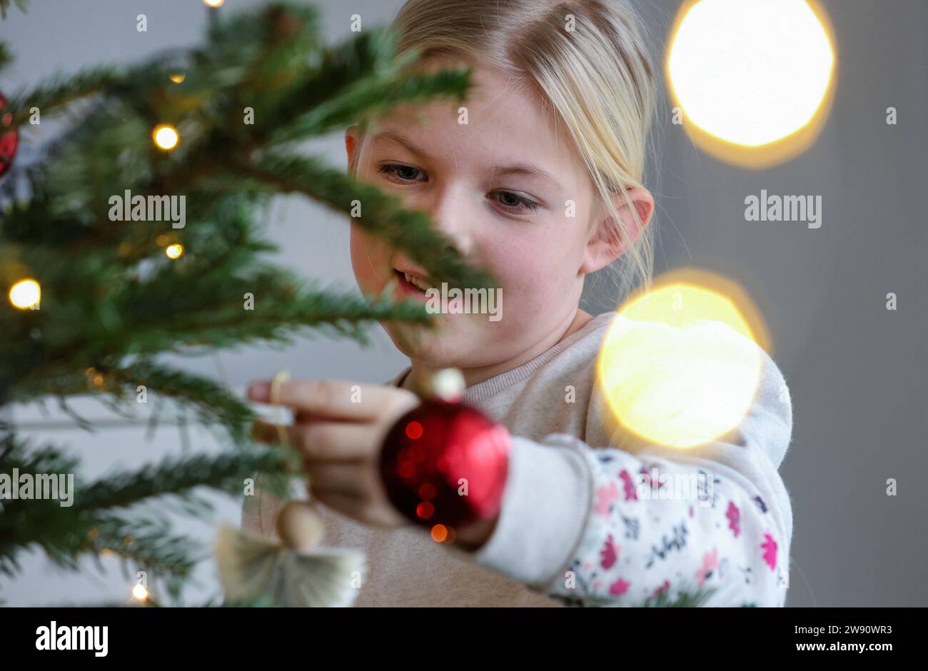 Riedlingen, Germany. 23rd Dec, 2023. Eight-year-old Jule decorates the ...