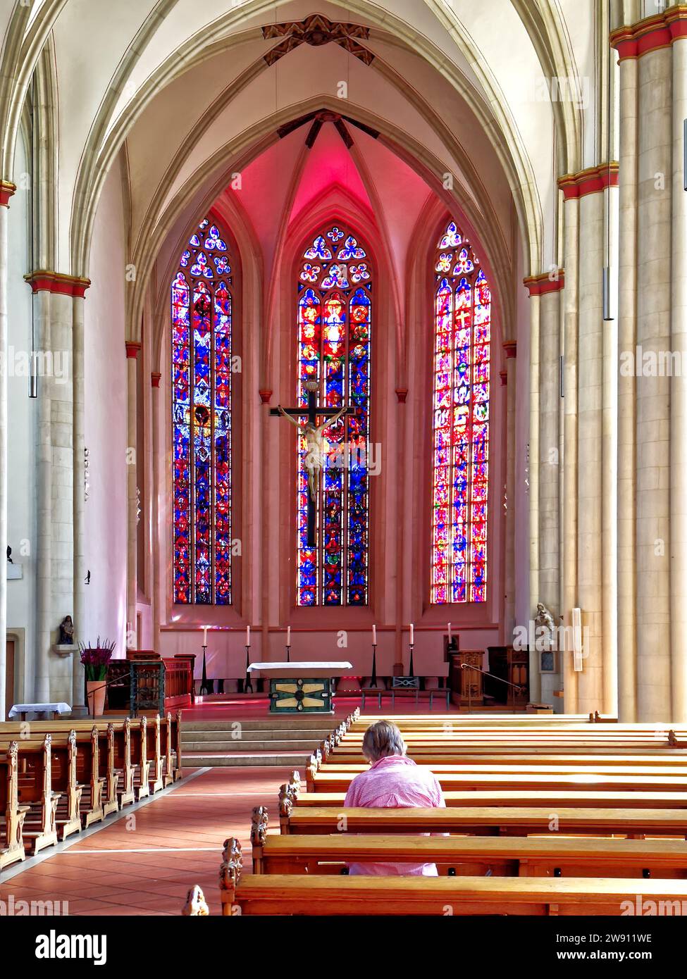 Woman sitting and praying in the church full of light and pink ...