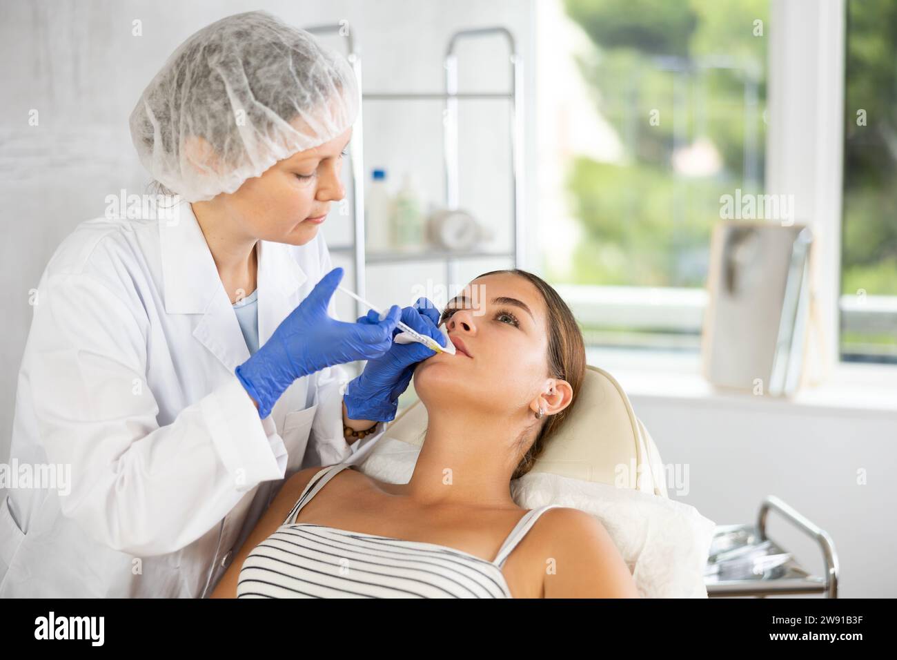 Doctor gives injection and performs procedure of lip augmentation of ...