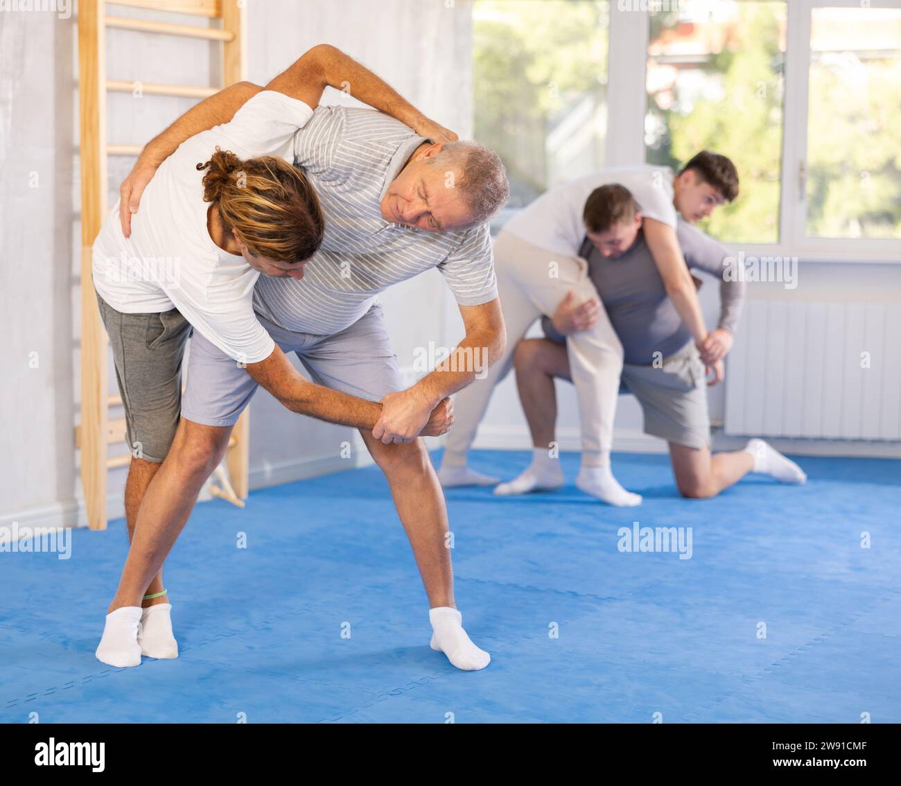 Old man practices hip flip technique with his sparring partner during ...