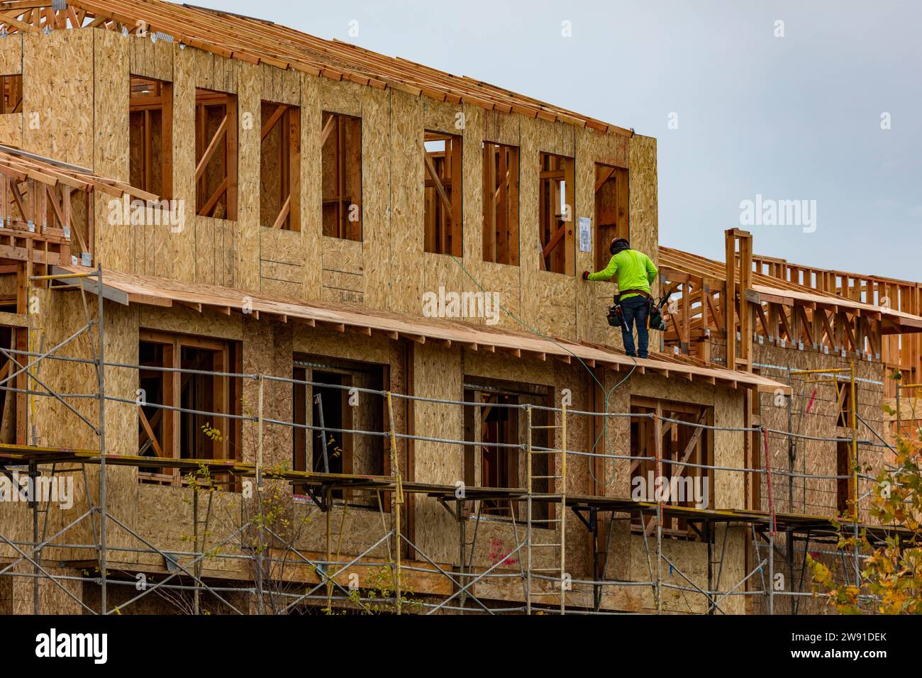 A construction worker working on a side of a framed building during ...