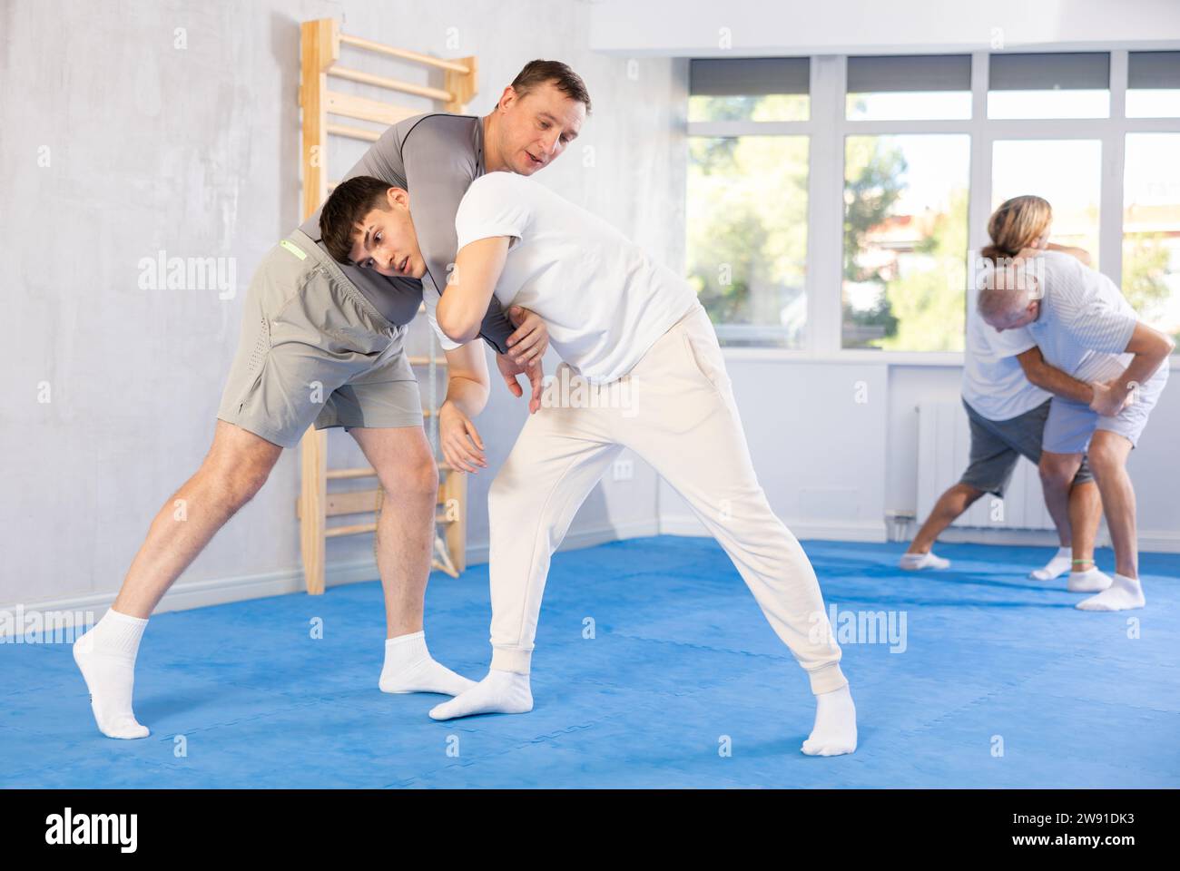 Man and young guy in group training fight in sparring and apply judo ...