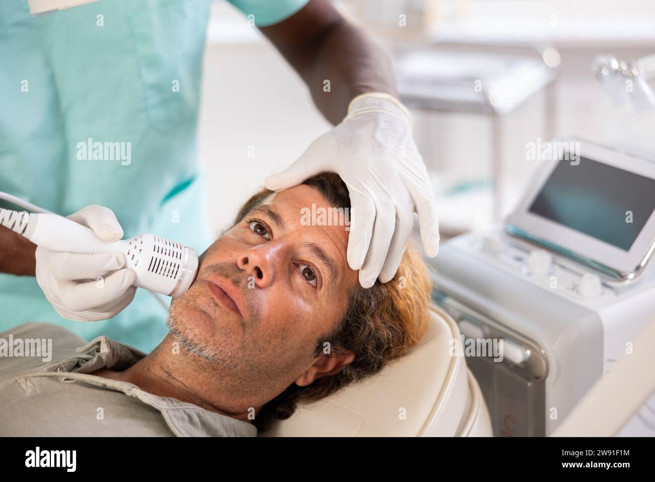 Middle-aged male patient experiencing facial cryotherapy procedure ...