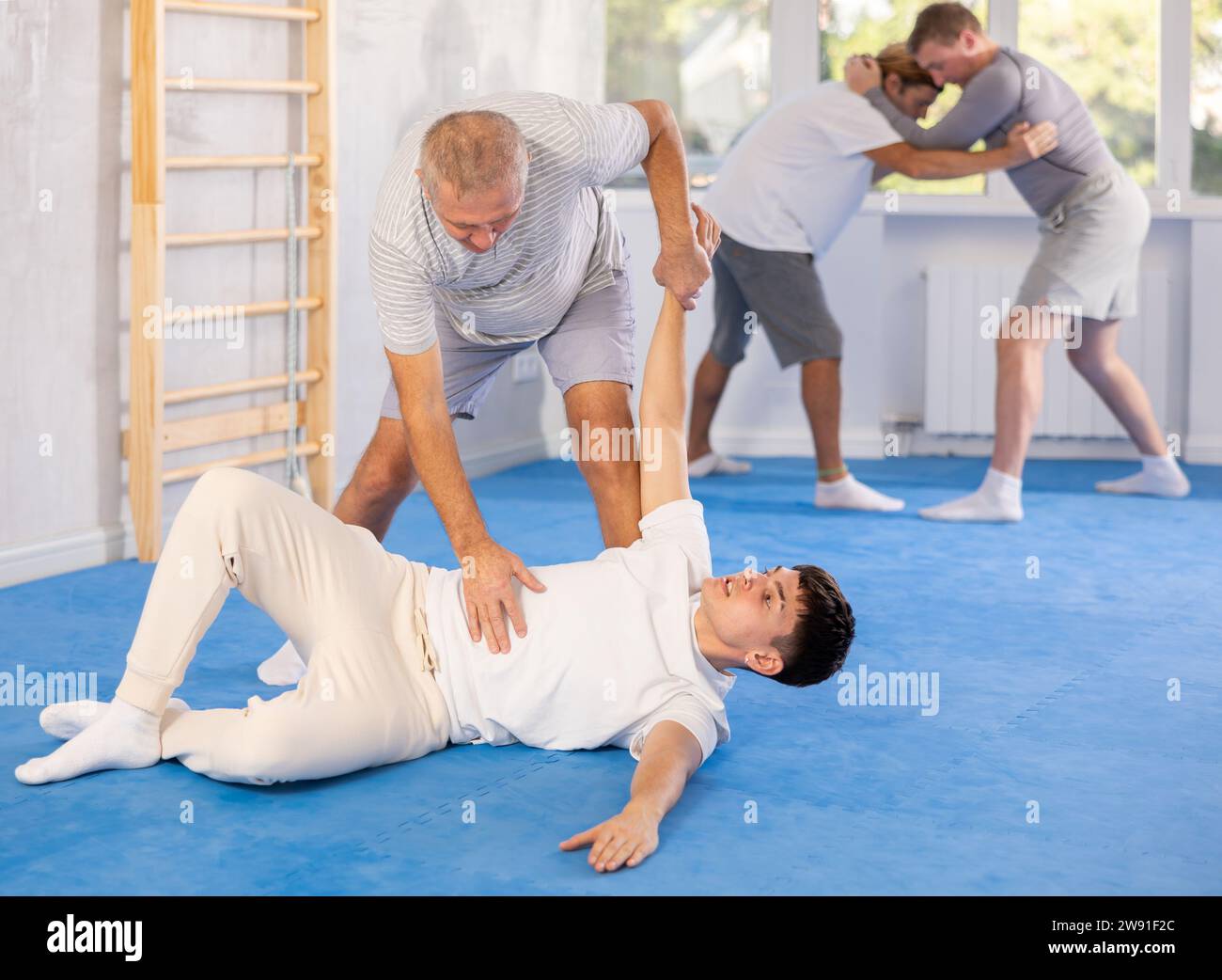 Two men of different ages in judo sparring - older man throws young guy ...
