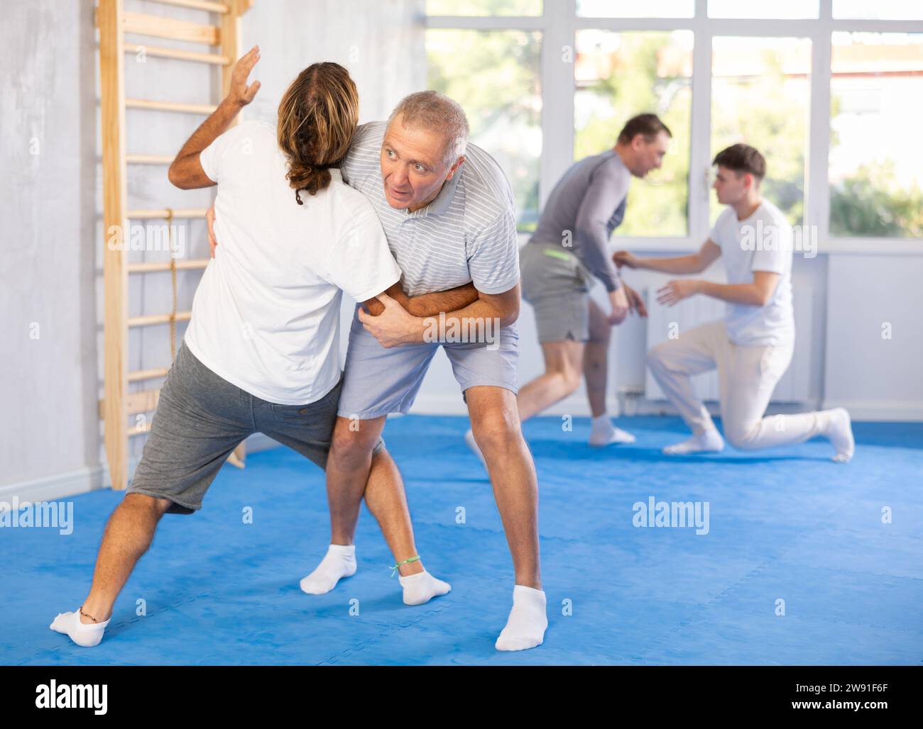 Old man practices hip flip technique with his sparring partner during ...