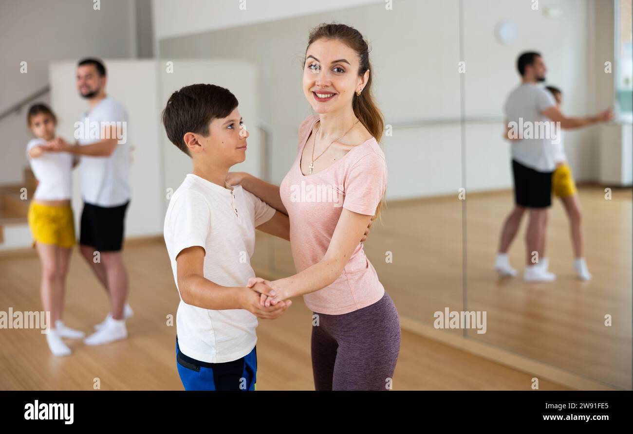 Young woman dancing waltz in pair with tween son during family dance ...