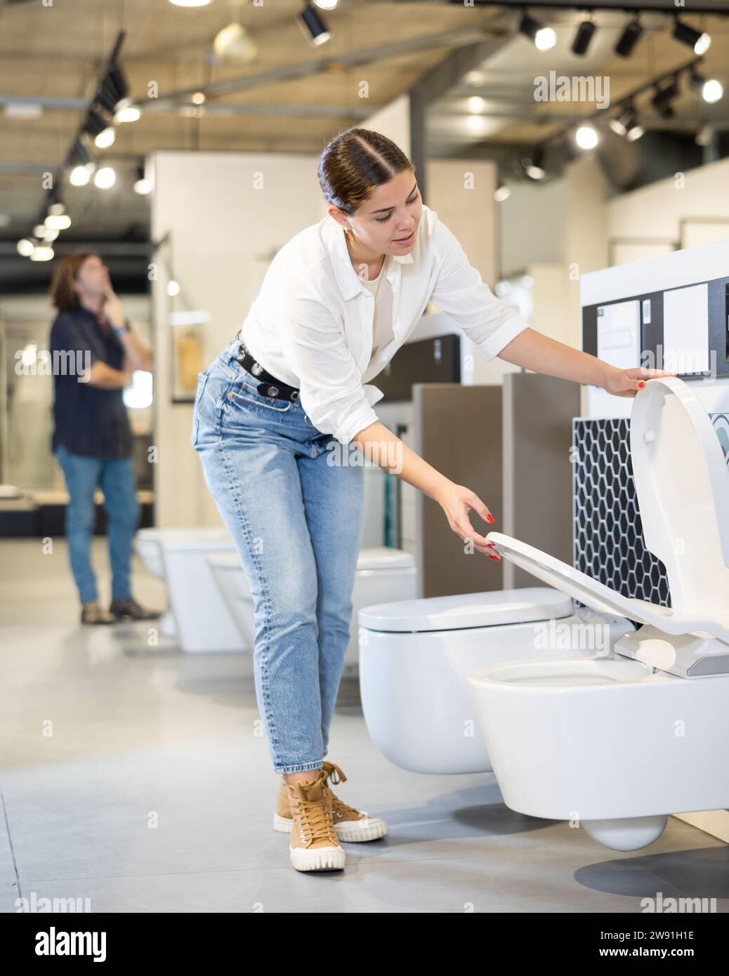 in plumbing department, female buyer checks for defects of toilet ...