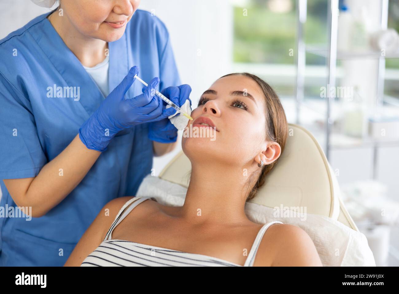 Cropped woman doctor performs procedure of introducing filler and ...