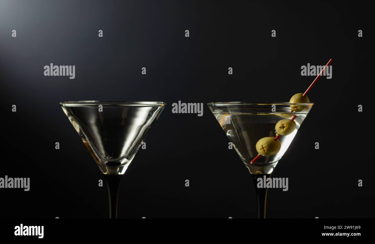 Classic dry martini cocktail with green olives on a black background ...