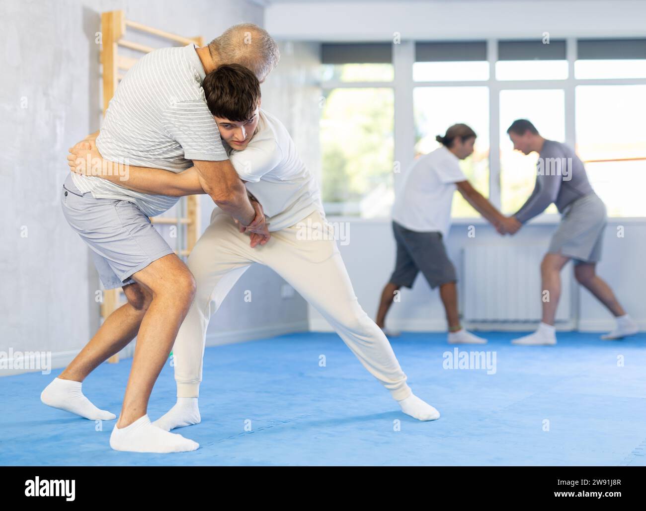 Two men of different ages in judo sparring - older man throws young guy ...