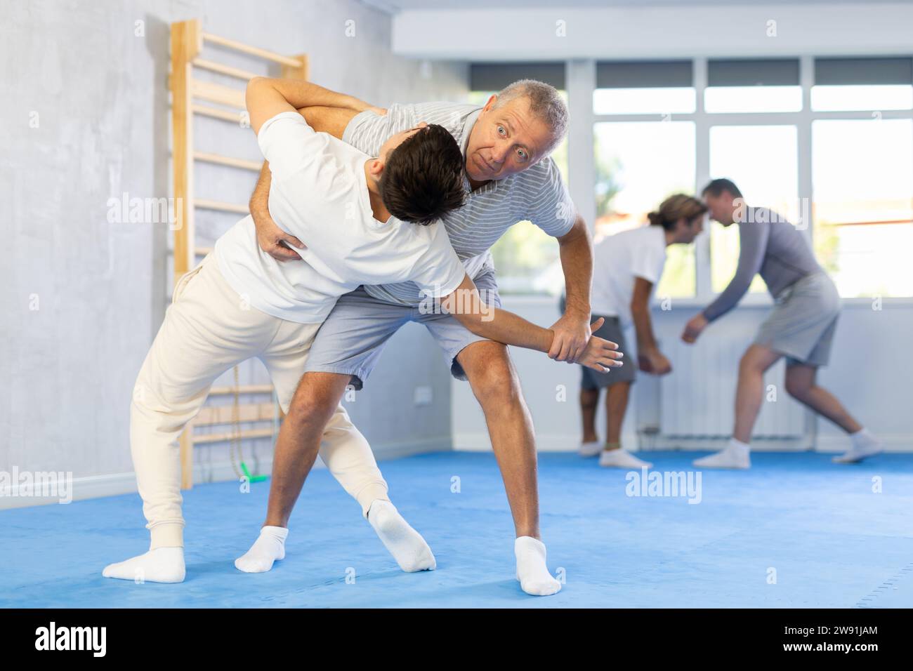 Two men of different ages in judo sparring - older man throws young guy ...