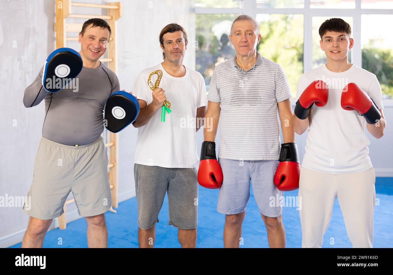Four men of different ages in gym at group training session looking ...