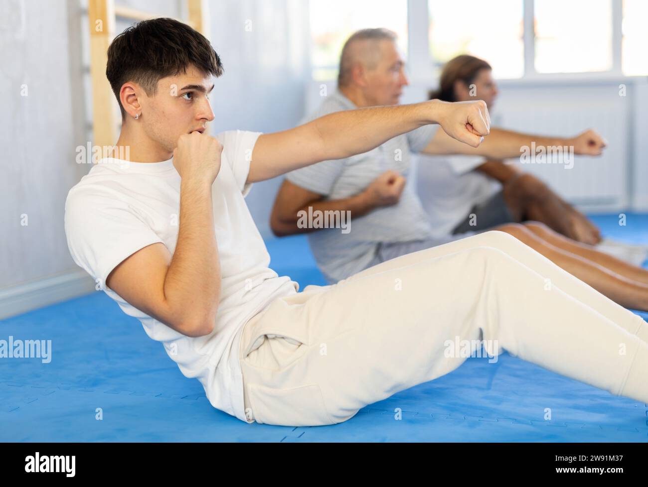 Group of men train abdominal muscles and do punches at the same time ...