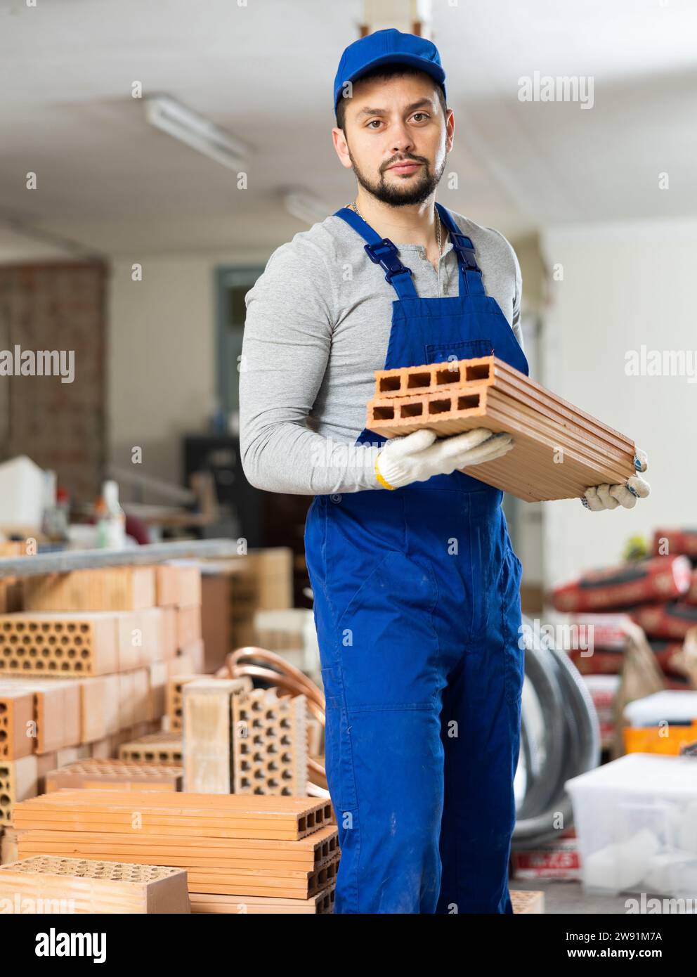 Young contractor stacking bricks on construction site indoors Stock ...