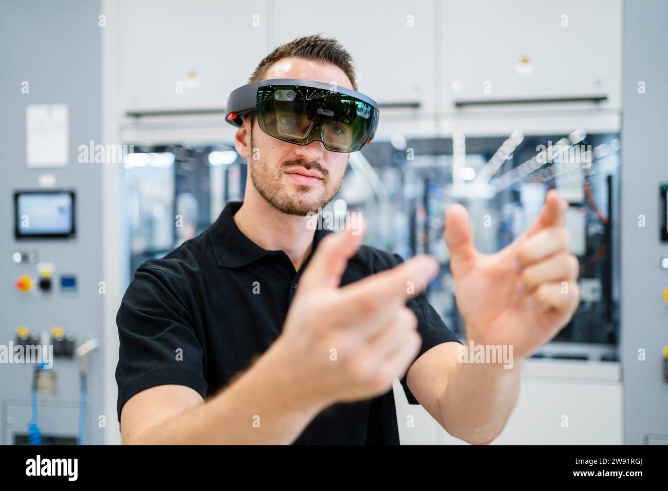 Technician wearing augmented reality glasses and gesturing in a factory ...