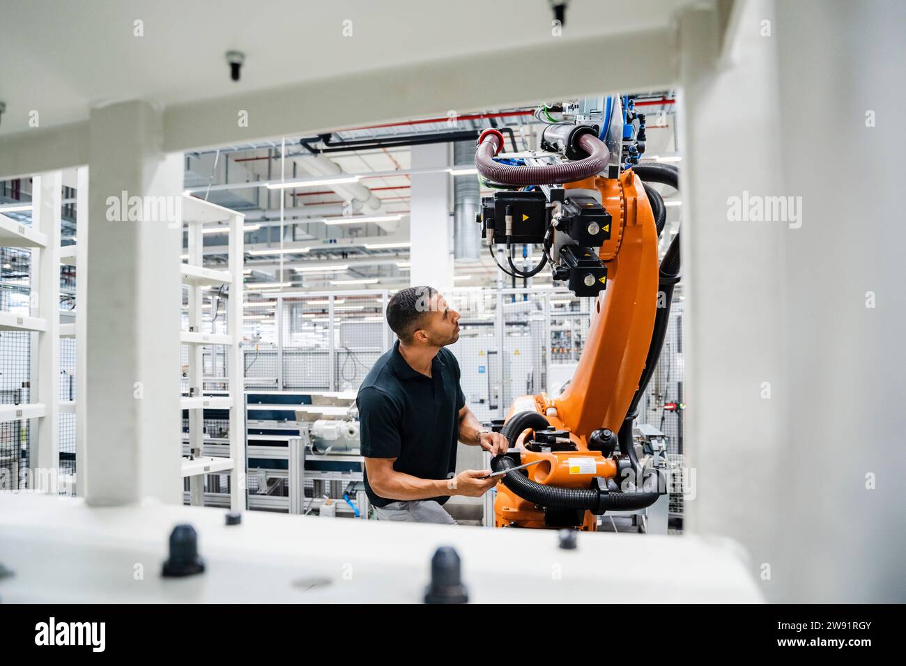 Technician examining industrial robot in a factory Stock Photo - Alamy