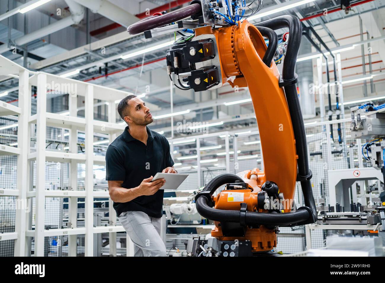 Technician examining industrial robot in a factory Stock Photo - Alamy