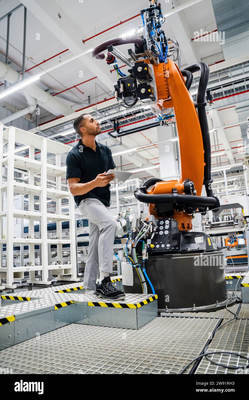Technician examining industrial robot in a factory Stock Photo - Alamy