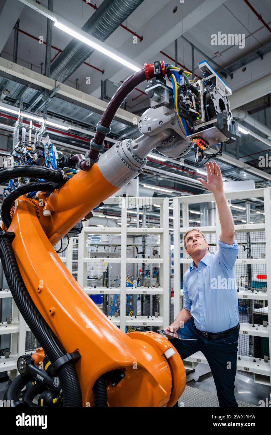 Businessman examining industrial robot in a factory Stock Photo - Alamy