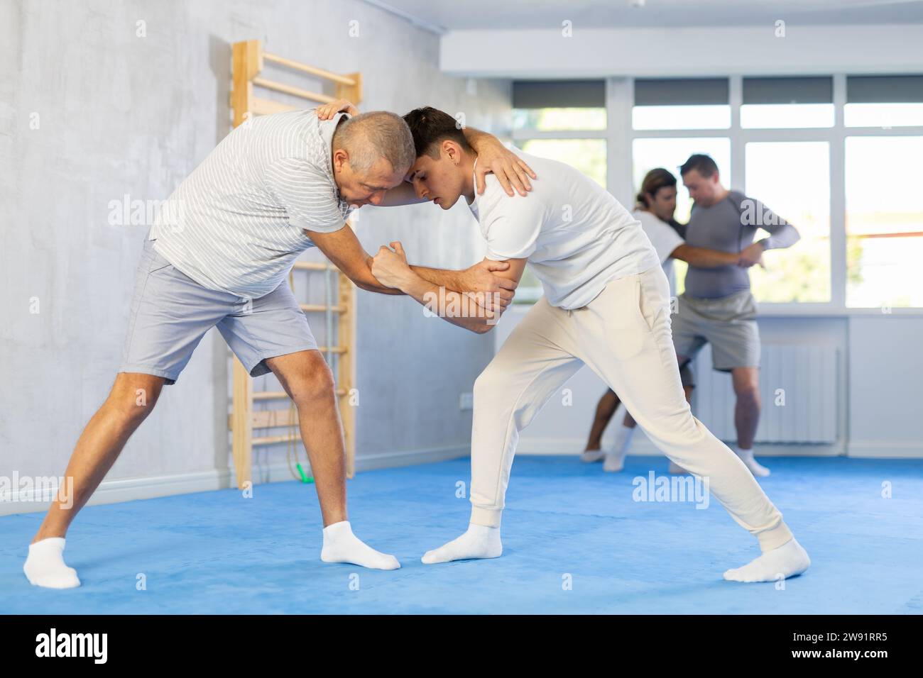 Two men of different ages in judo sparring - older man throws young guy ...