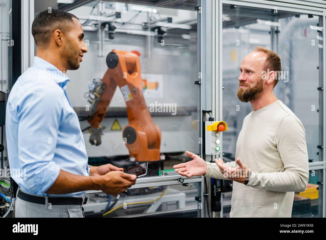 Employee and businessman talking at industrial robot in a factory Stock ...
