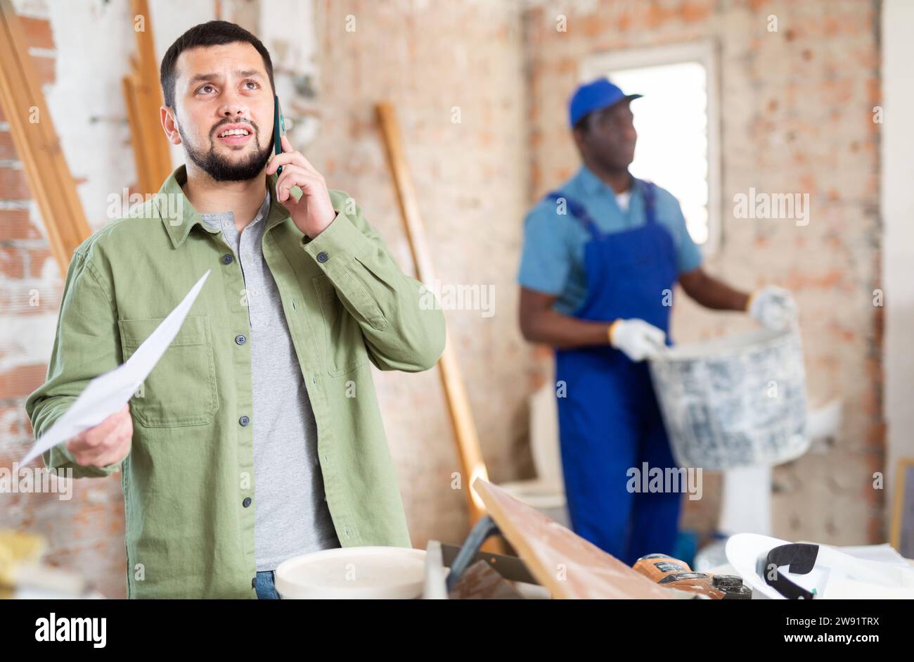 Man architect having telephone conversation about project documentation ...