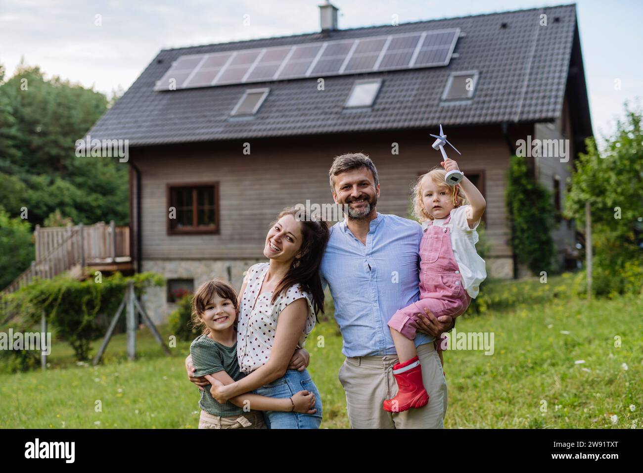Young family having fun in front their family house with solar panels ...