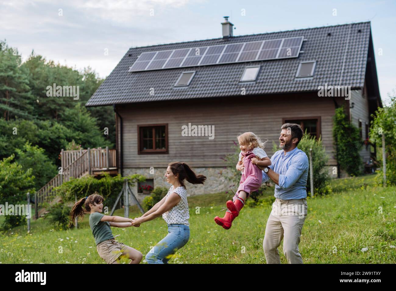 Young family having fun in front their family house with solar panels ...