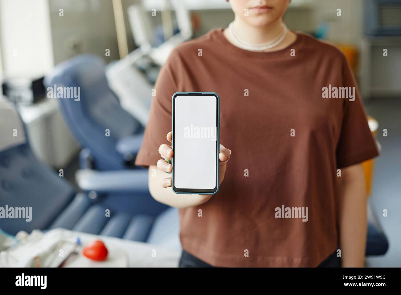 Woman showing blank display of smart phone screen at blood donation ...