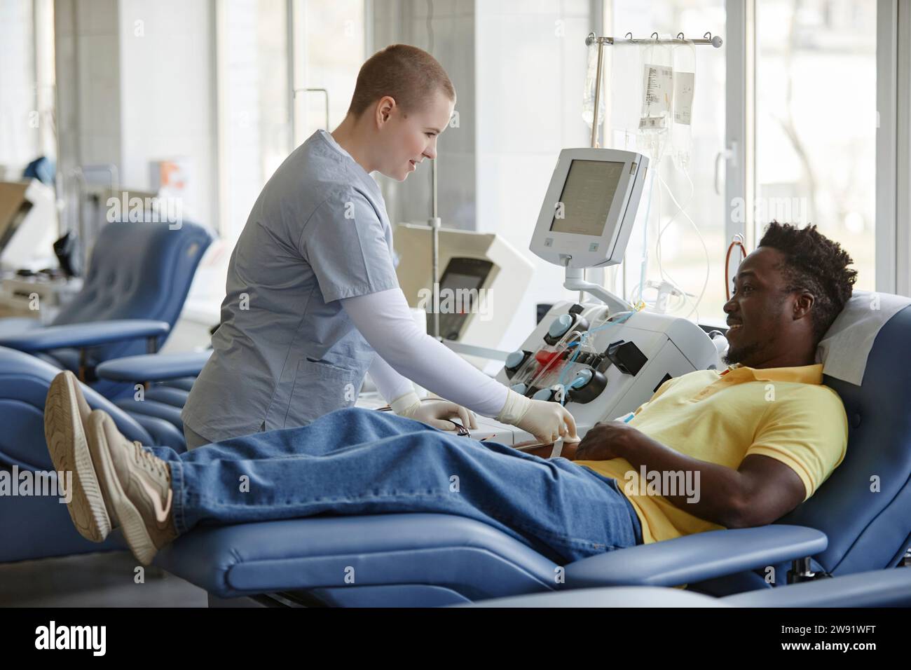 Healthcare worker assisting donor reclining on couch at blood donation ...