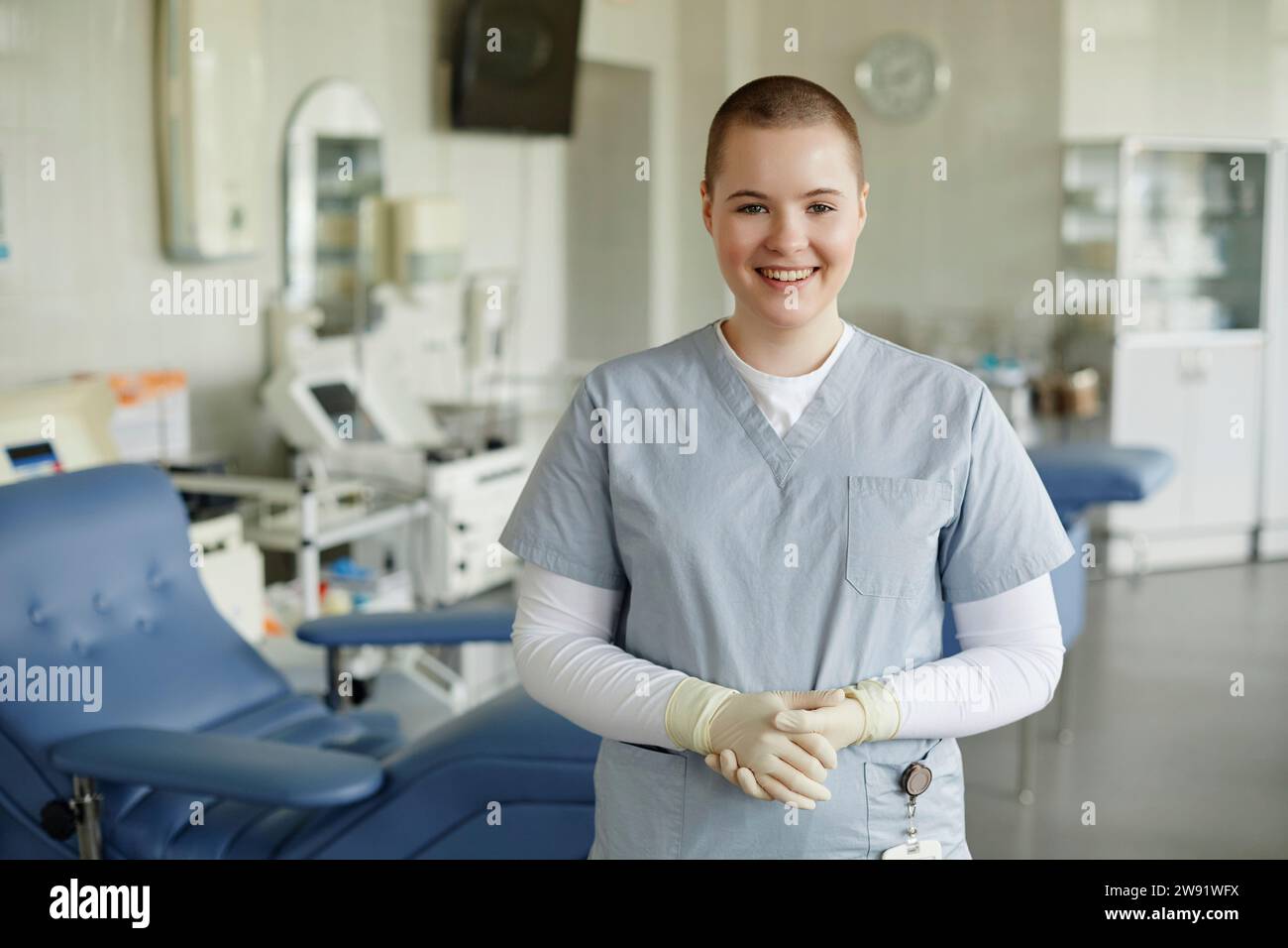 Smiling healthcare worker standing with hands clasped at blood donation ...
