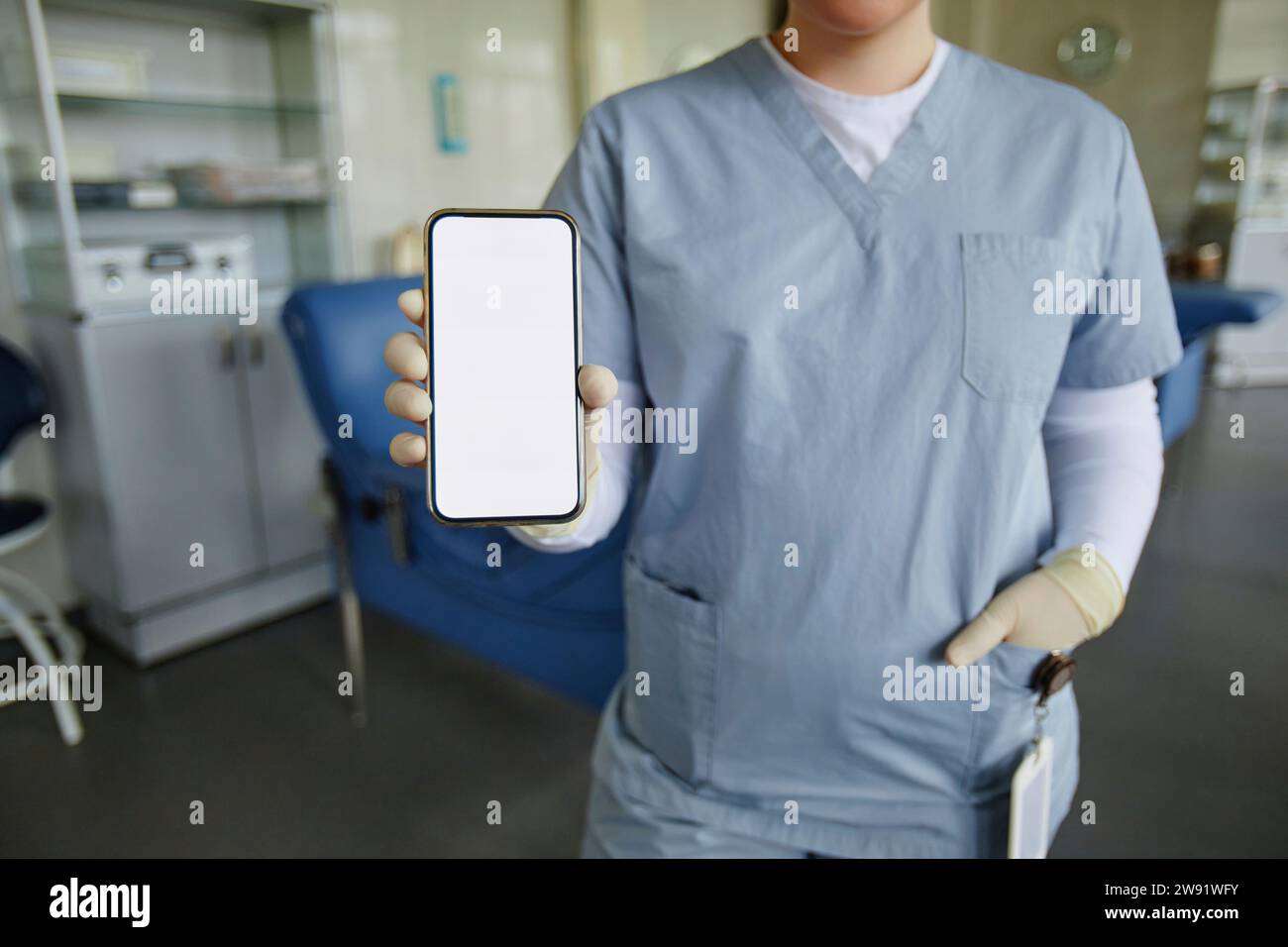 Healthcare worker with hand in pocket showing white screen of smart ...