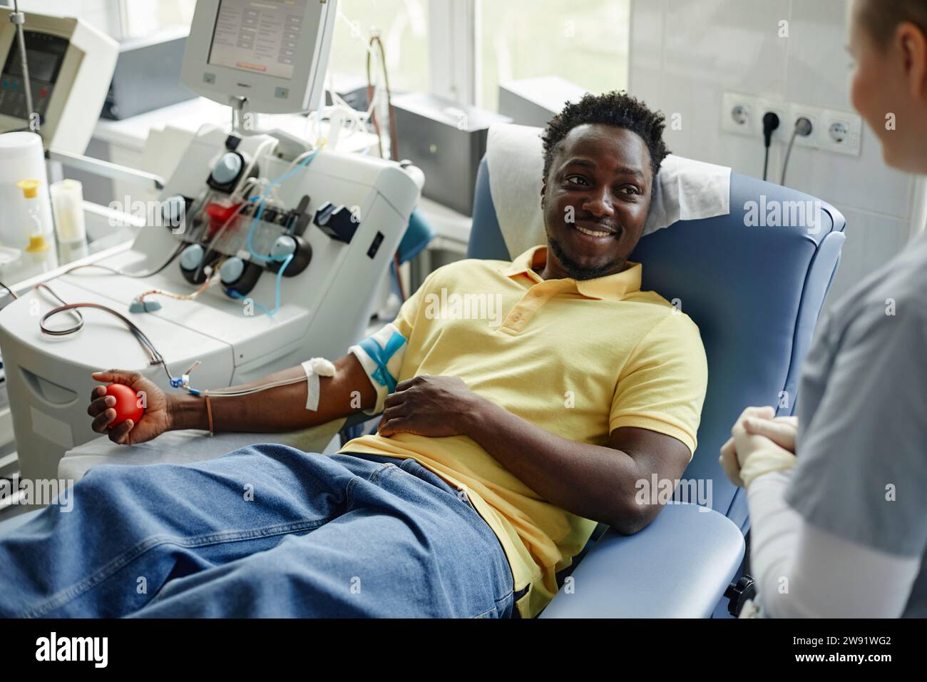 Smiling donor talking with healthcare worker at blood donation center ...