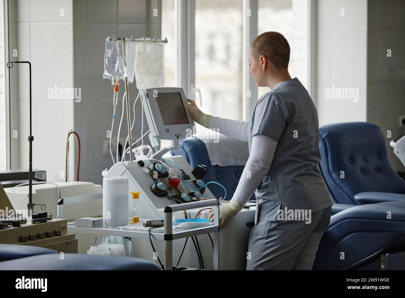 Young healthcare worker operating equipment at blood donation center ...