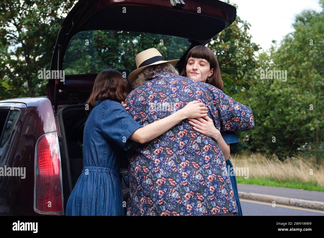 Daughters hugging father near car trunk Stock Photo - Alamy