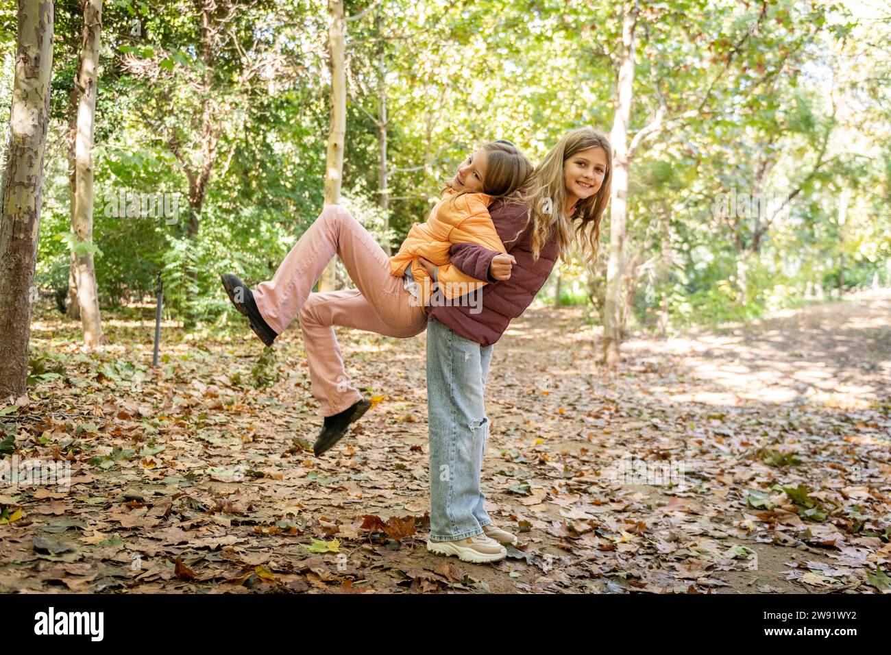 Smiling girl giving piggyback ride to friend in park Stock Photo - Alamy