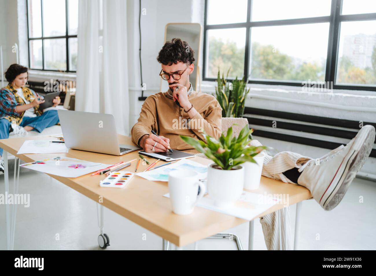 Thoughtful illustrator working with feet up at desk in office Stock ...