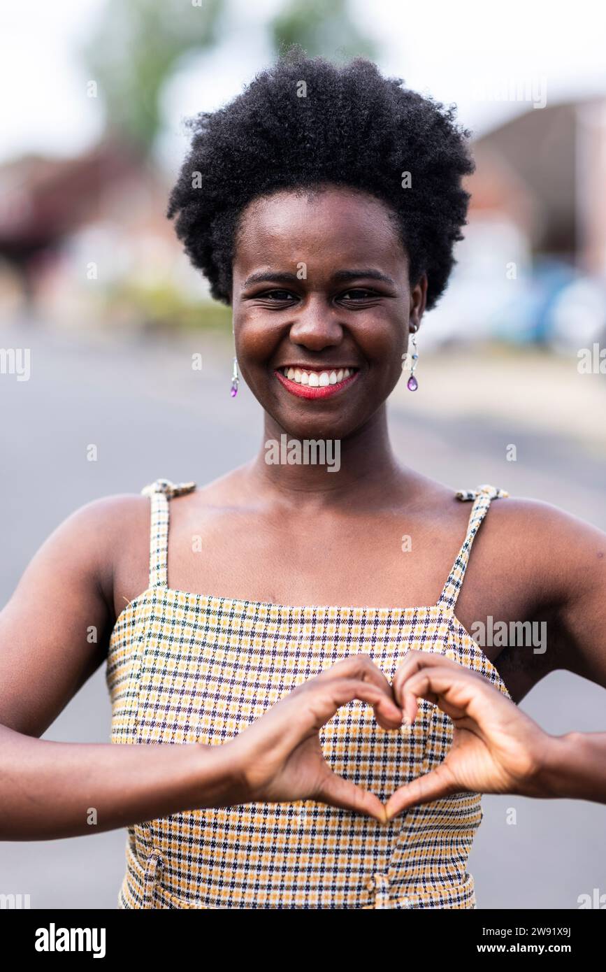 Happy young woman gesturing heart shape Stock Photo - Alamy