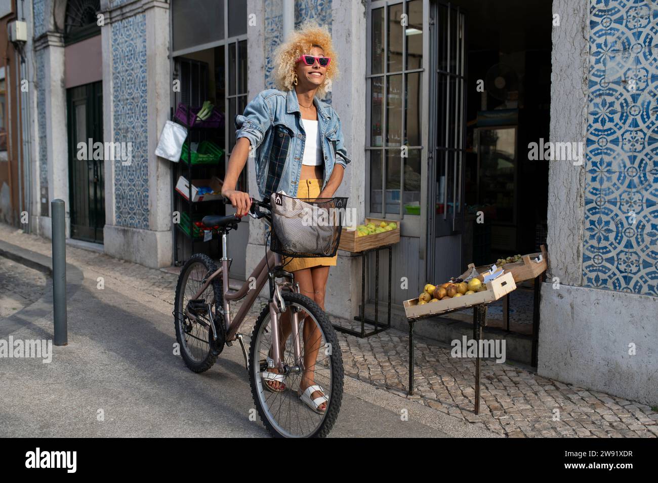 Smiling transgender woman wheeling with bicycle on street Stock Photo ...