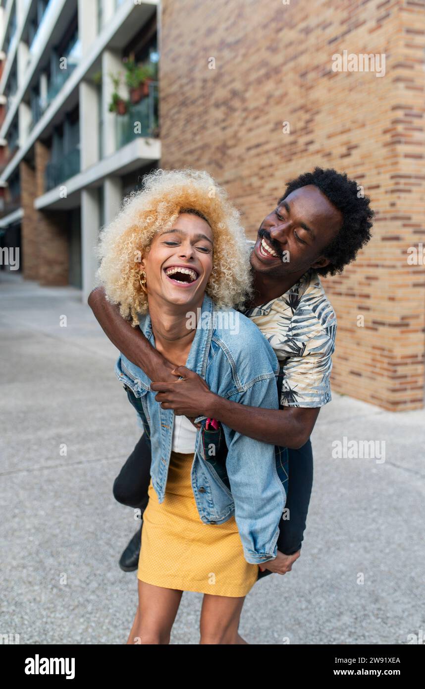 Happy transgender woman piggybacking boyfriend in front of building ...