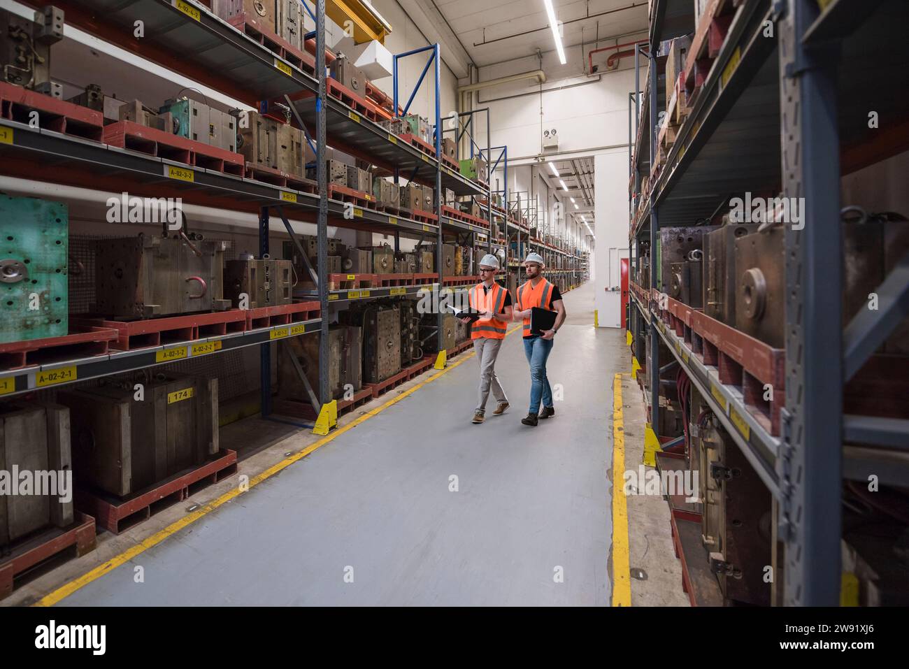 Colleagues examining shelves at warehouse in factory Stock Photo - Alamy