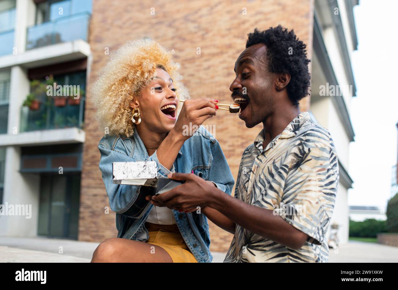 Happy transgender woman feeding sushi to boyfriend Stock Photo - Alamy