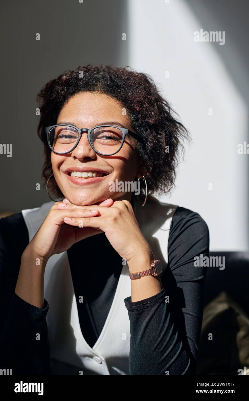 Smiling young businesswoman wearing eyeglasses sitting in office Stock ...