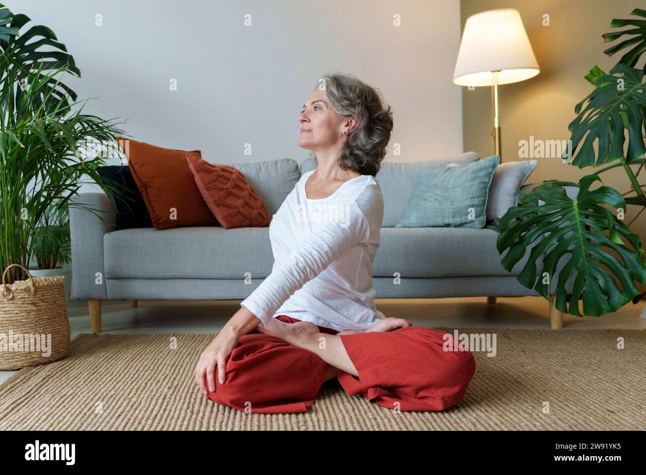 Woman practicing yoga pose sitting on rug at home Stock Photo - Alamy