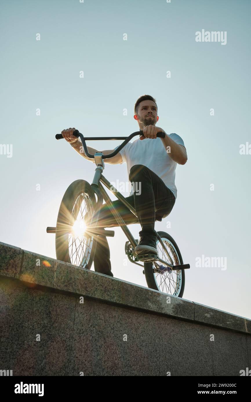 Man riding BMX bike on wall under sky Stock Photo - Alamy