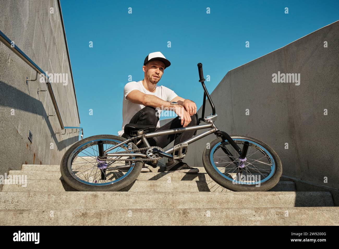 Thoughtful man sitting with BMX bike on staircase Stock Photo - Alamy