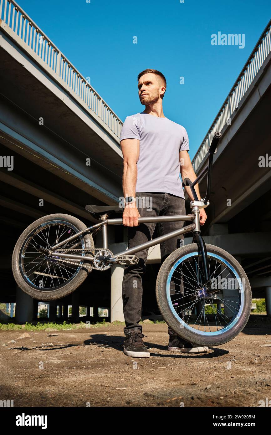 Man holding BMX bike near bridge under sky Stock Photo - Alamy